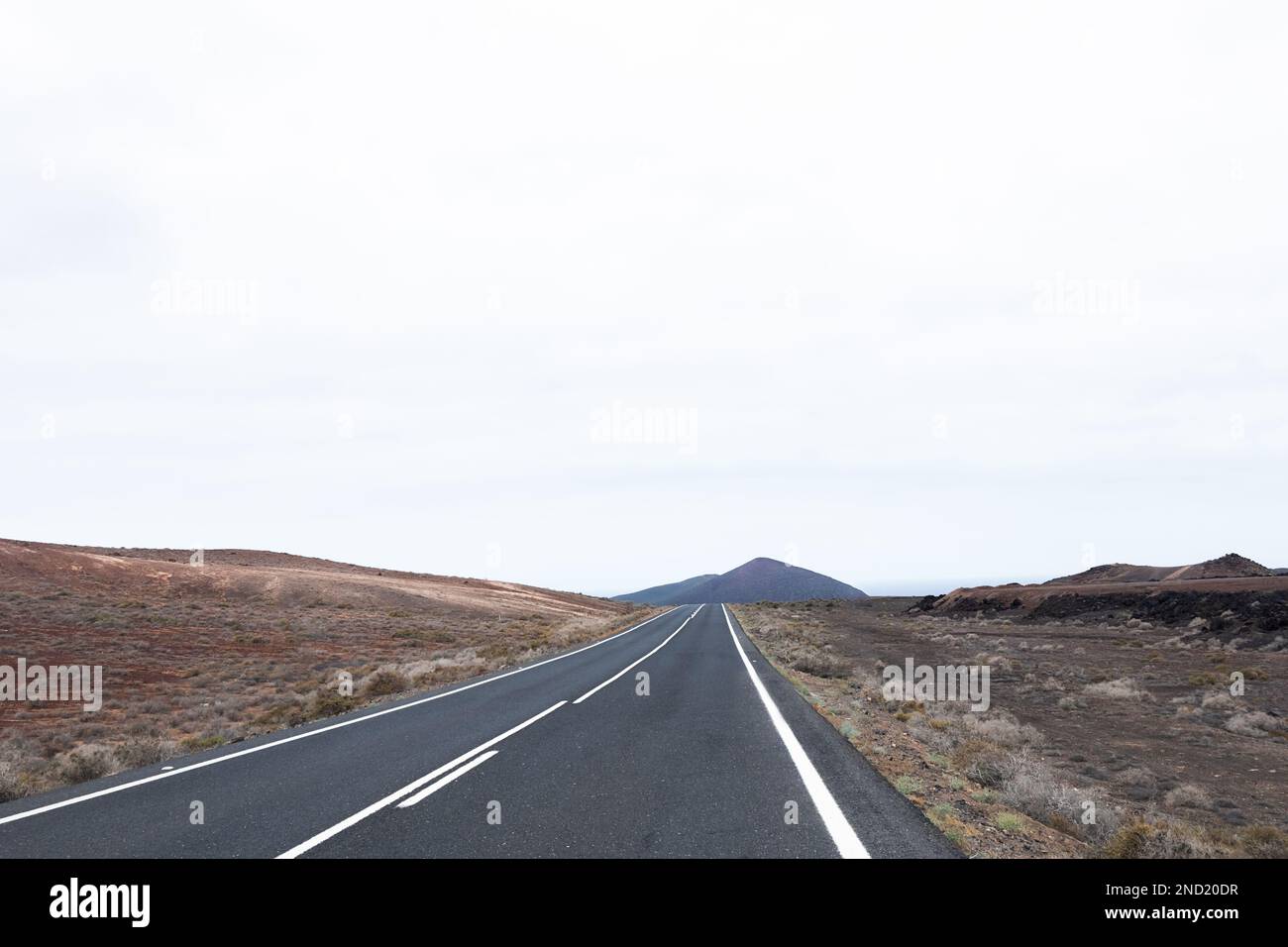 Empty asphalt road going through hilly terrain with dry grass against ...