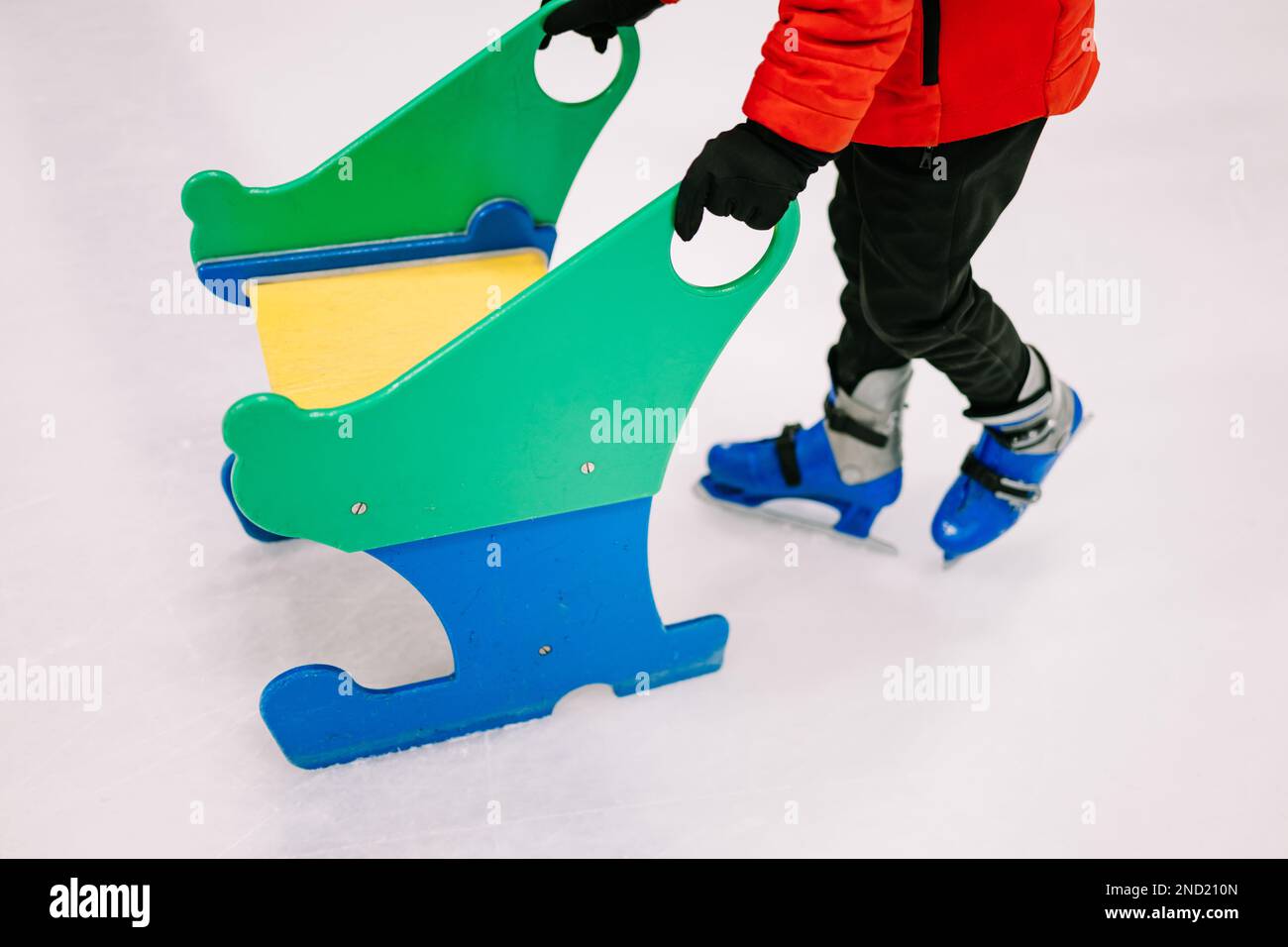 Back view boy in warm clothes and protective helmet learning ice ...