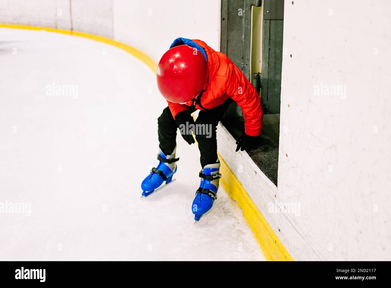 Unrecognizable boy in protective helmet and ice skates leaning on ...