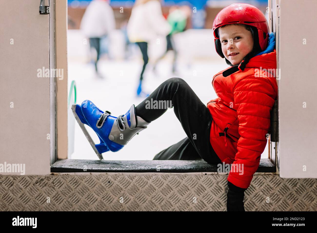 Side view of focused boy in safety helmet and warm clothes with skates ...