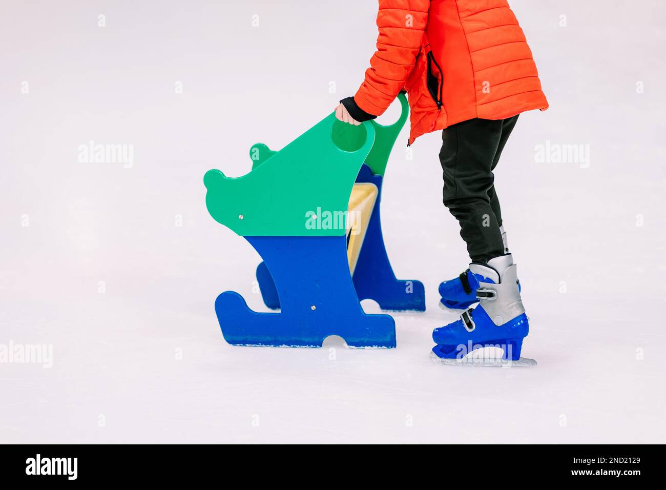 Side view boy in warm clothes and protective helmet learning ice ...