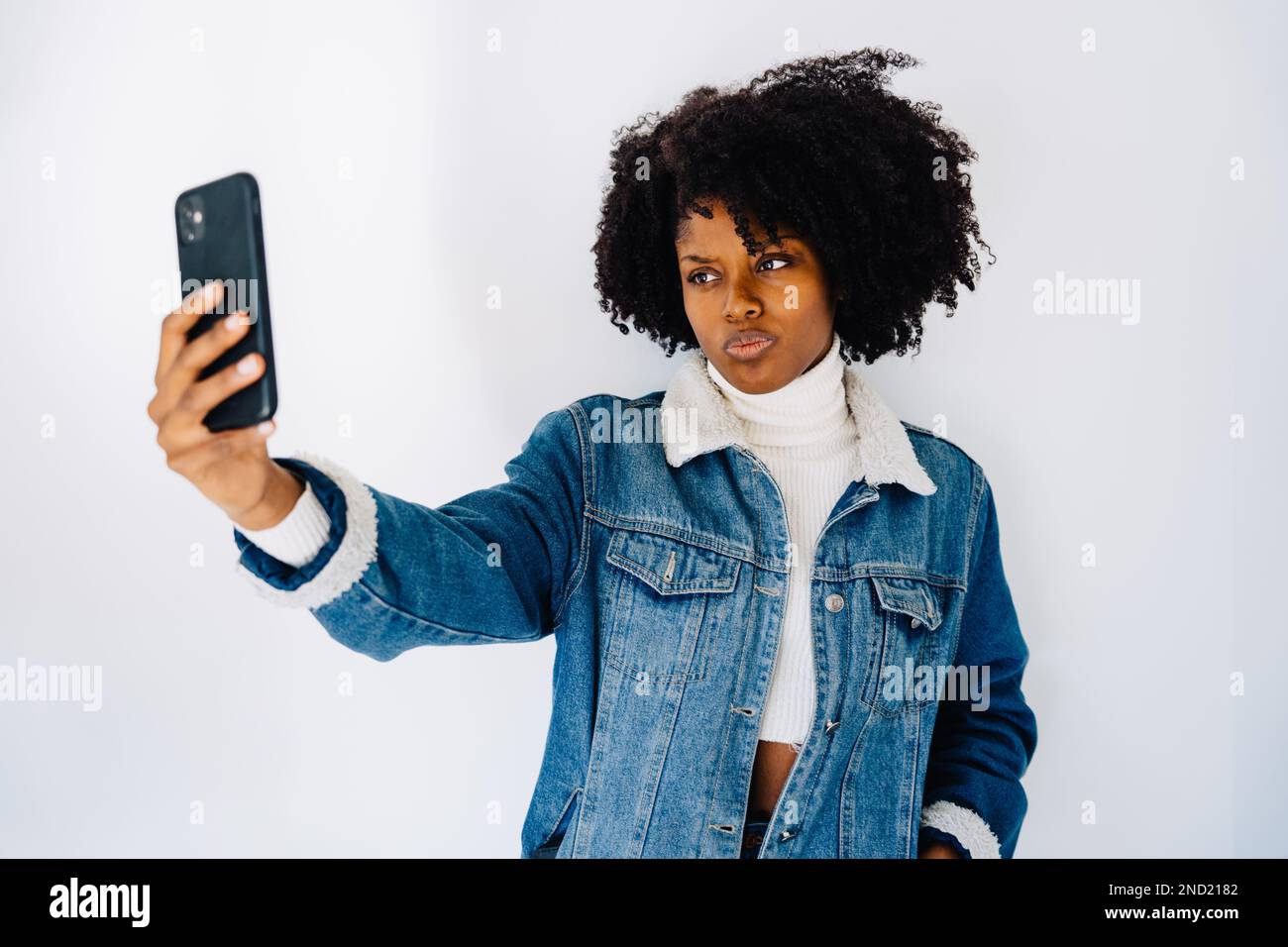 Optimistic young African American female with Afro hairstyle in denim ...