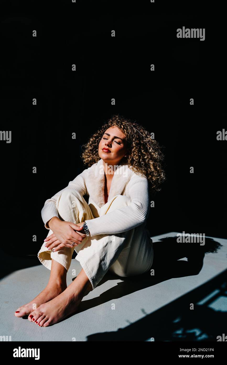 Full body high angle of young curly haired female with closed eyes ...