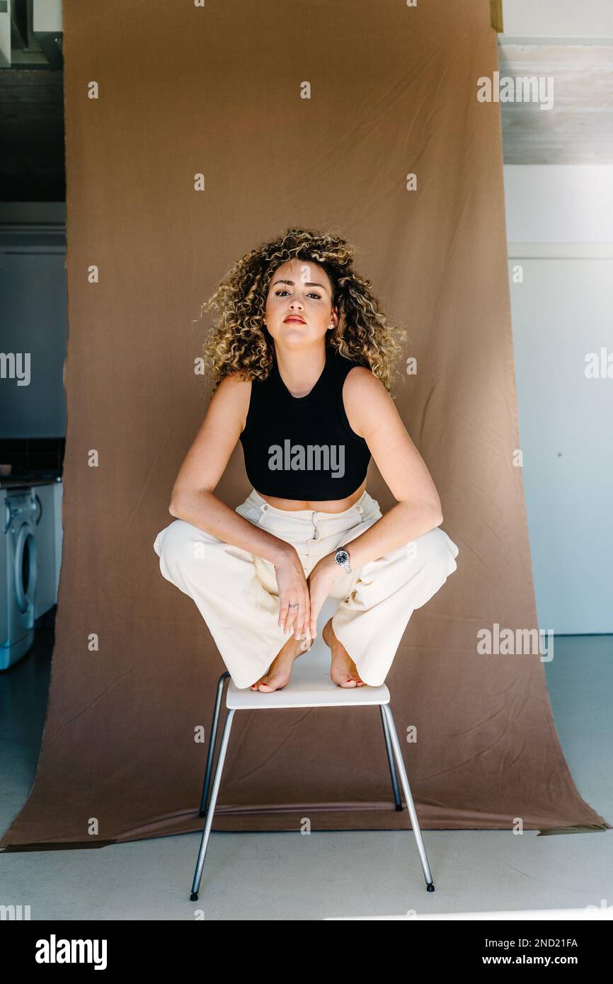 Full body of serious young curly haired female in top and pants on ...