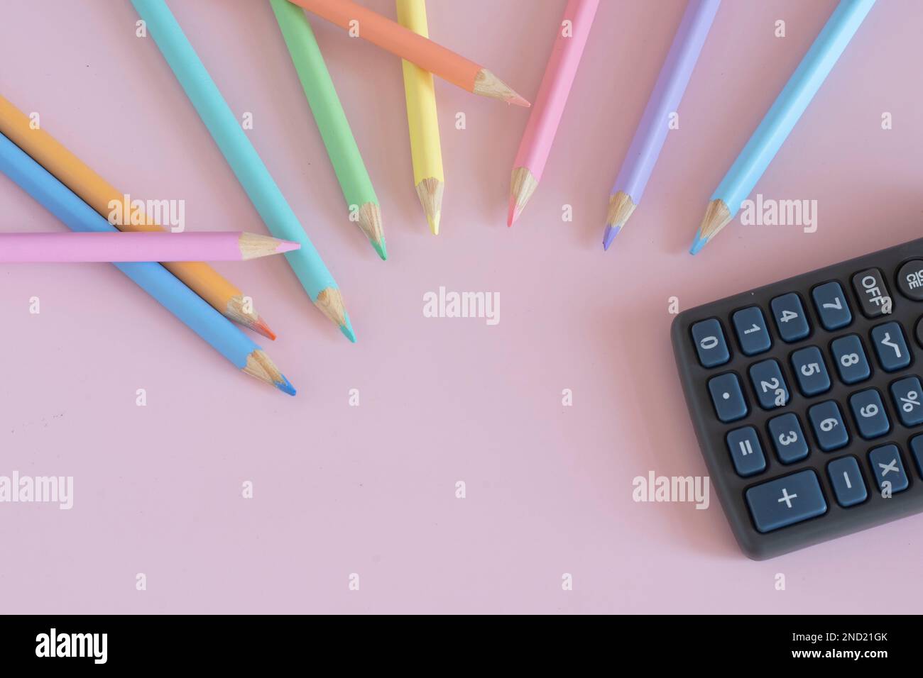 Pastel colored pencils with a calculator, top view on pink background ...