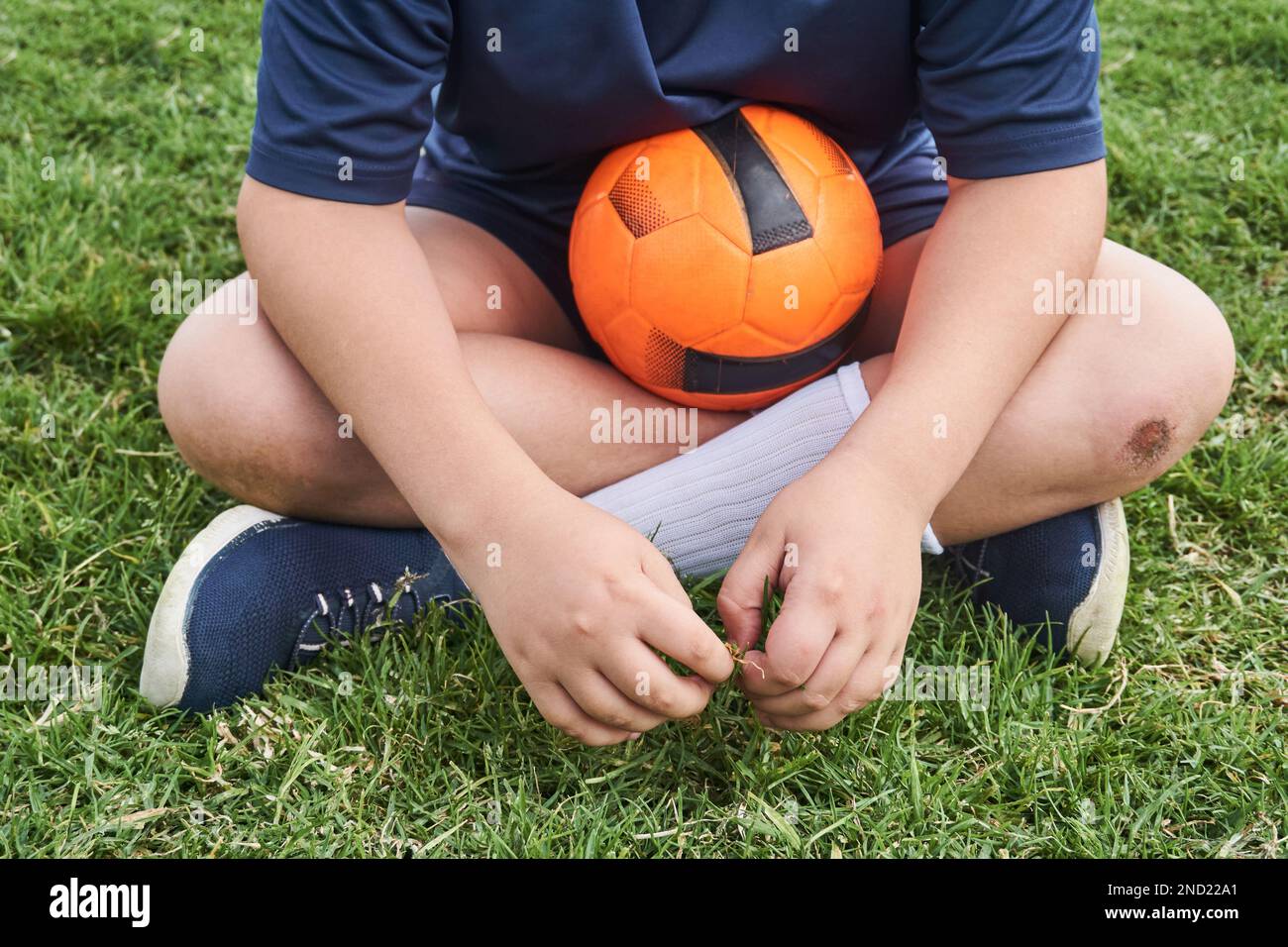 Preteen boy in sportswear sitting on football field with ball Stock ...