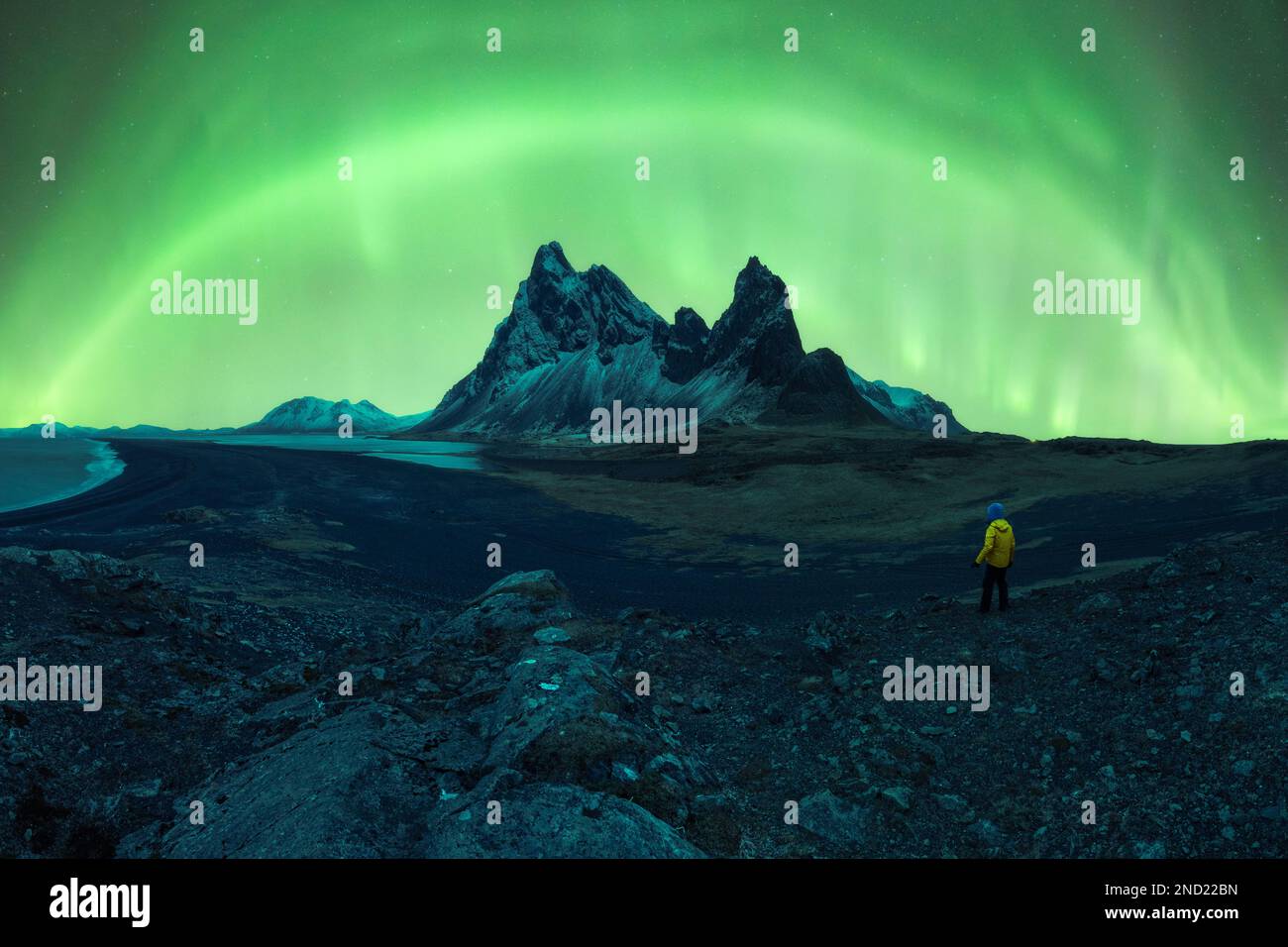 Anonymous tourist standing bear shore with calm sea and rough mountains ...
