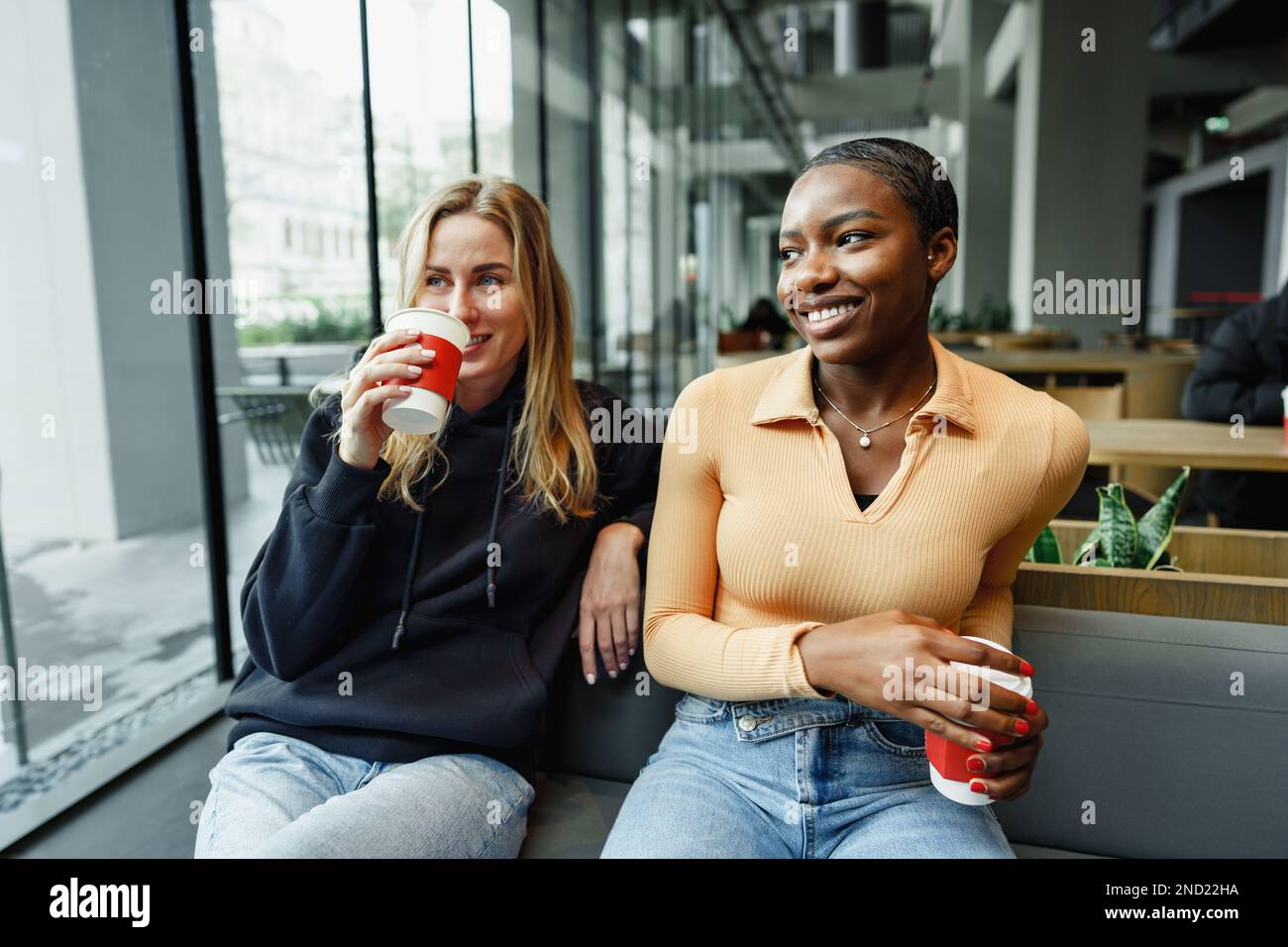 Two young women friends enjoying coffee together in a coffee shop Stock ...