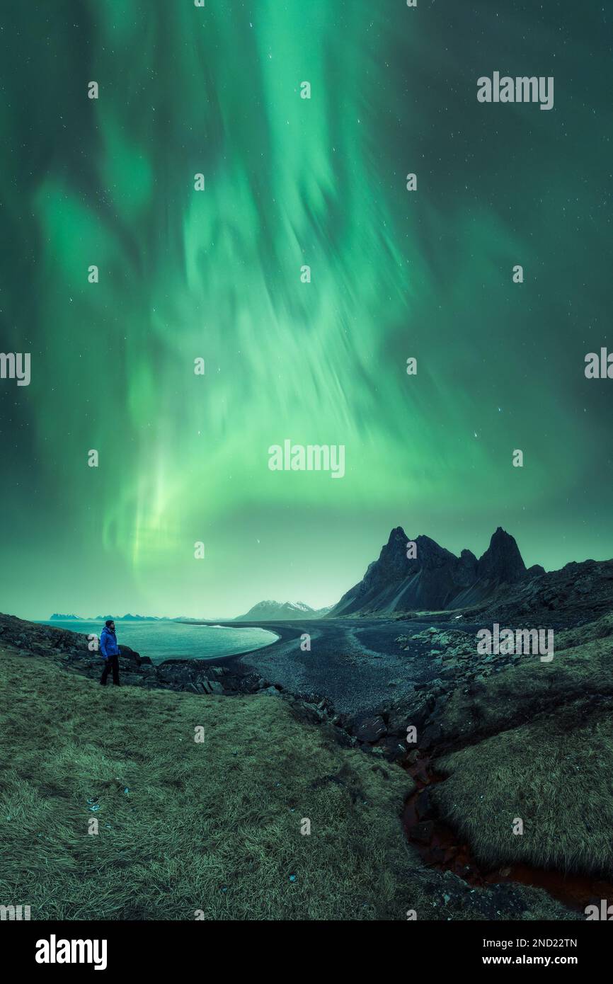 Anonymous tourist standing bear shore with calm sea and rough mountains ...