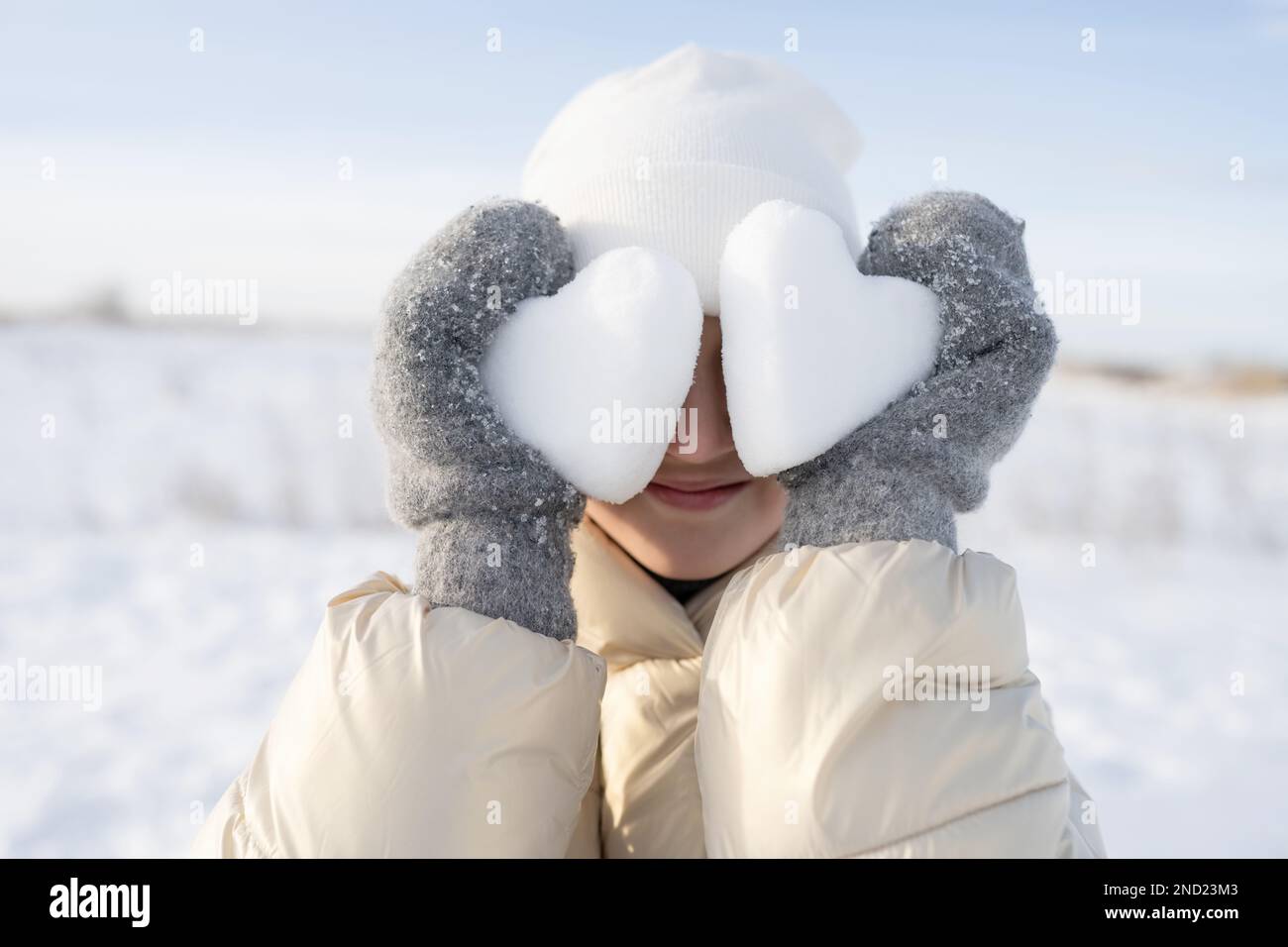 Calm teen girl in warm clothes and hat wearing mittens standing ...