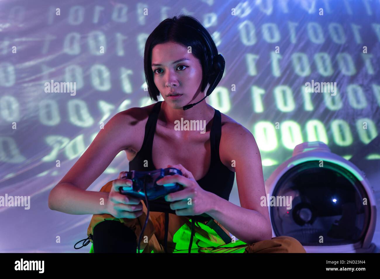 Serious young female in headphones with joystick playing video game ...