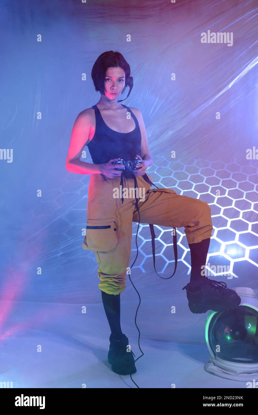 Full body of serious young female in headphones with joystick playing ...