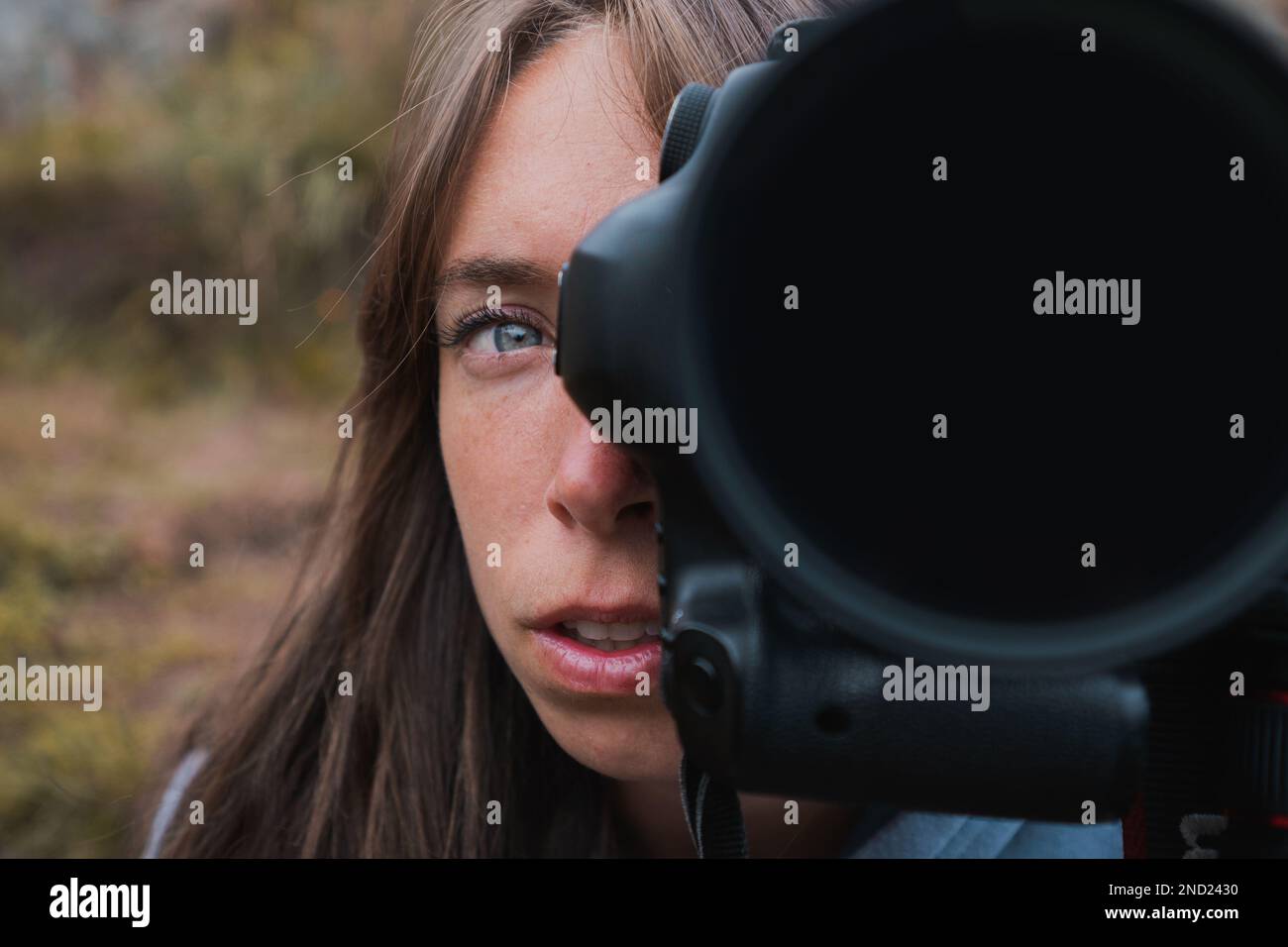 Crop female photographer hiding behind professional photo camera ...