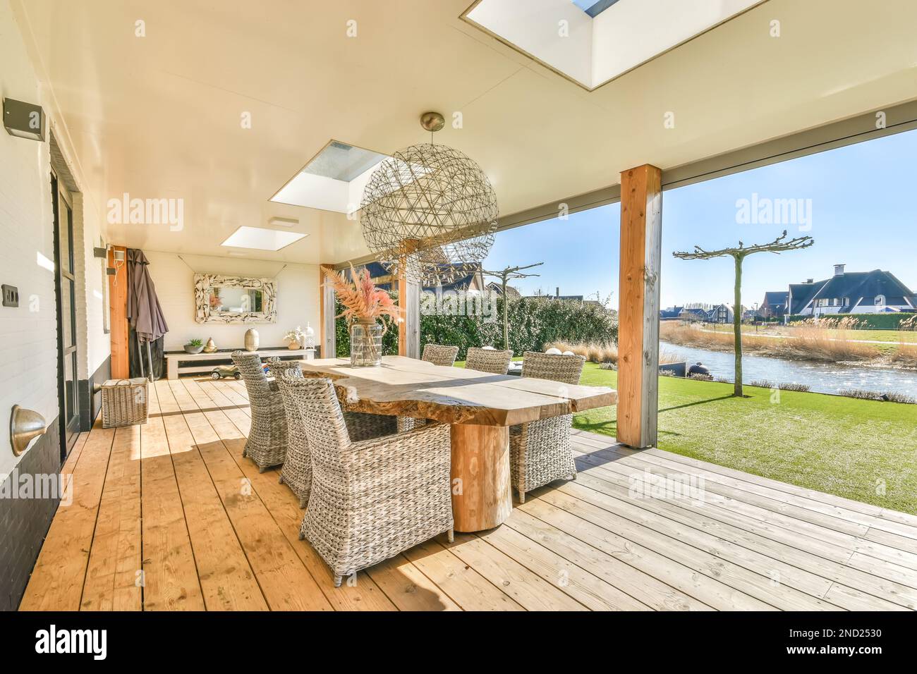 Wooden table with chairs under round spherical chandelier on terrace of ...