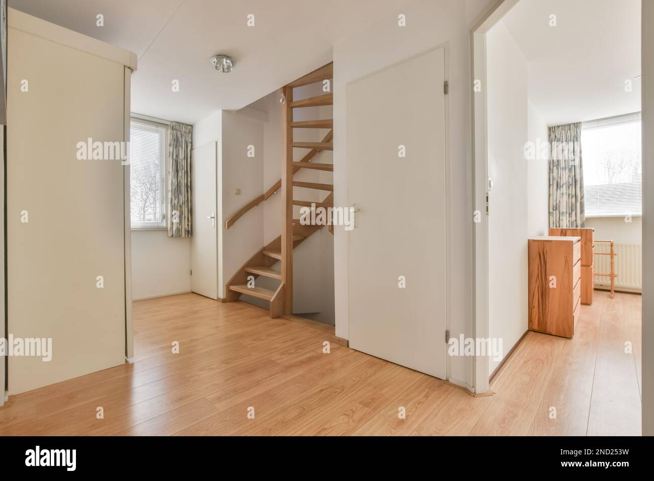 Corridor with wooden stairs and parquet floor against white walls and ...