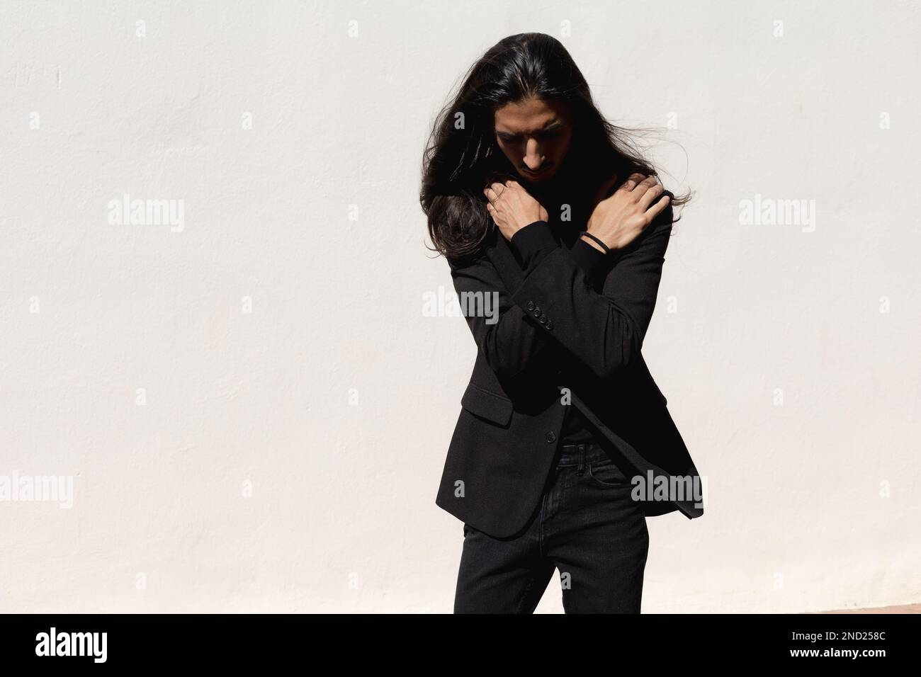 Serious Hispanic male model with long hair wearing black classy outfit ...