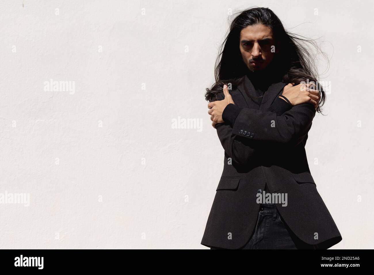 Serious Hispanic male model with long hair wearing black classy outfit ...