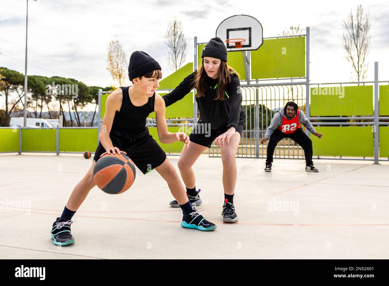 Full body of boy in sportswear dribbling ball teen girl in defence ...