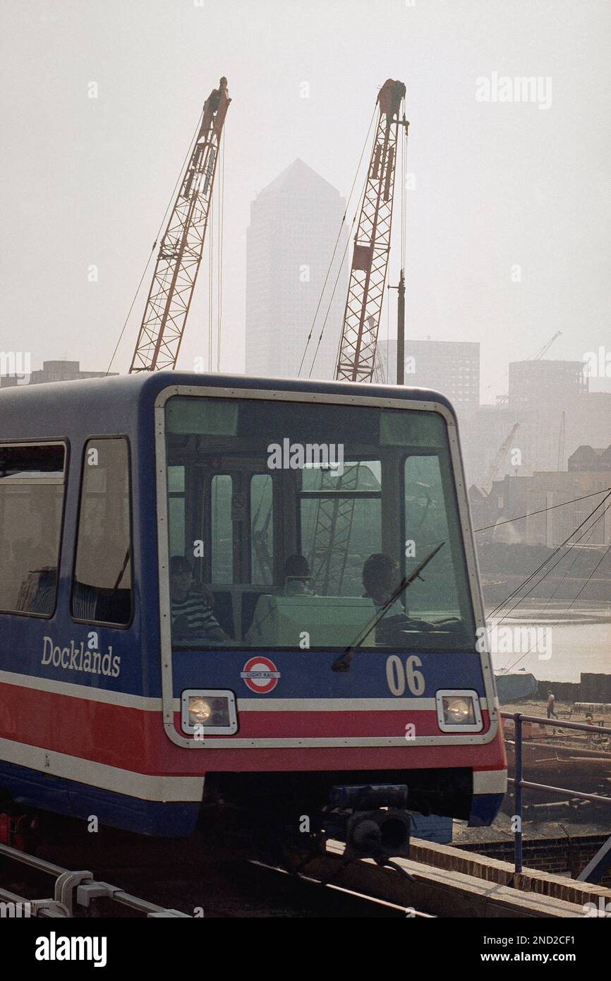 A Docklands Light Railway train passes in front of huge cranes which ...