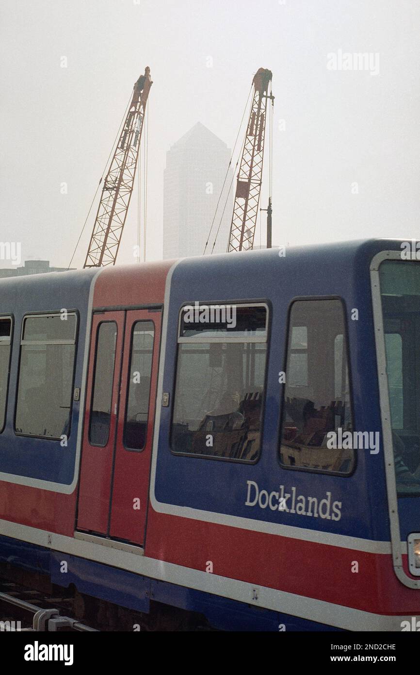 A Docklands Light Railway train passes in front of huge cranes which ...
