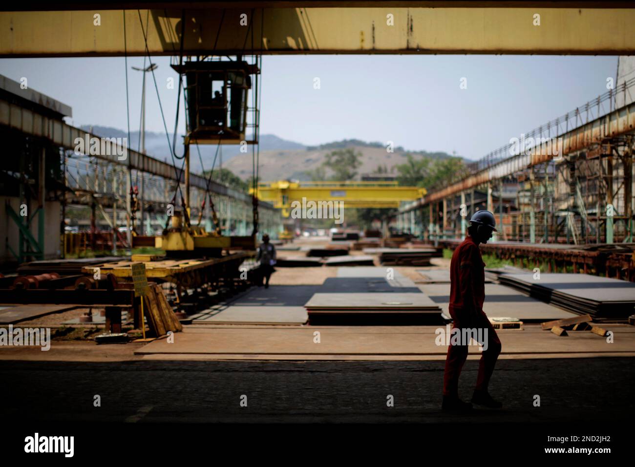 A Petrobras oil worker walks by iron sheets to be used in the ...