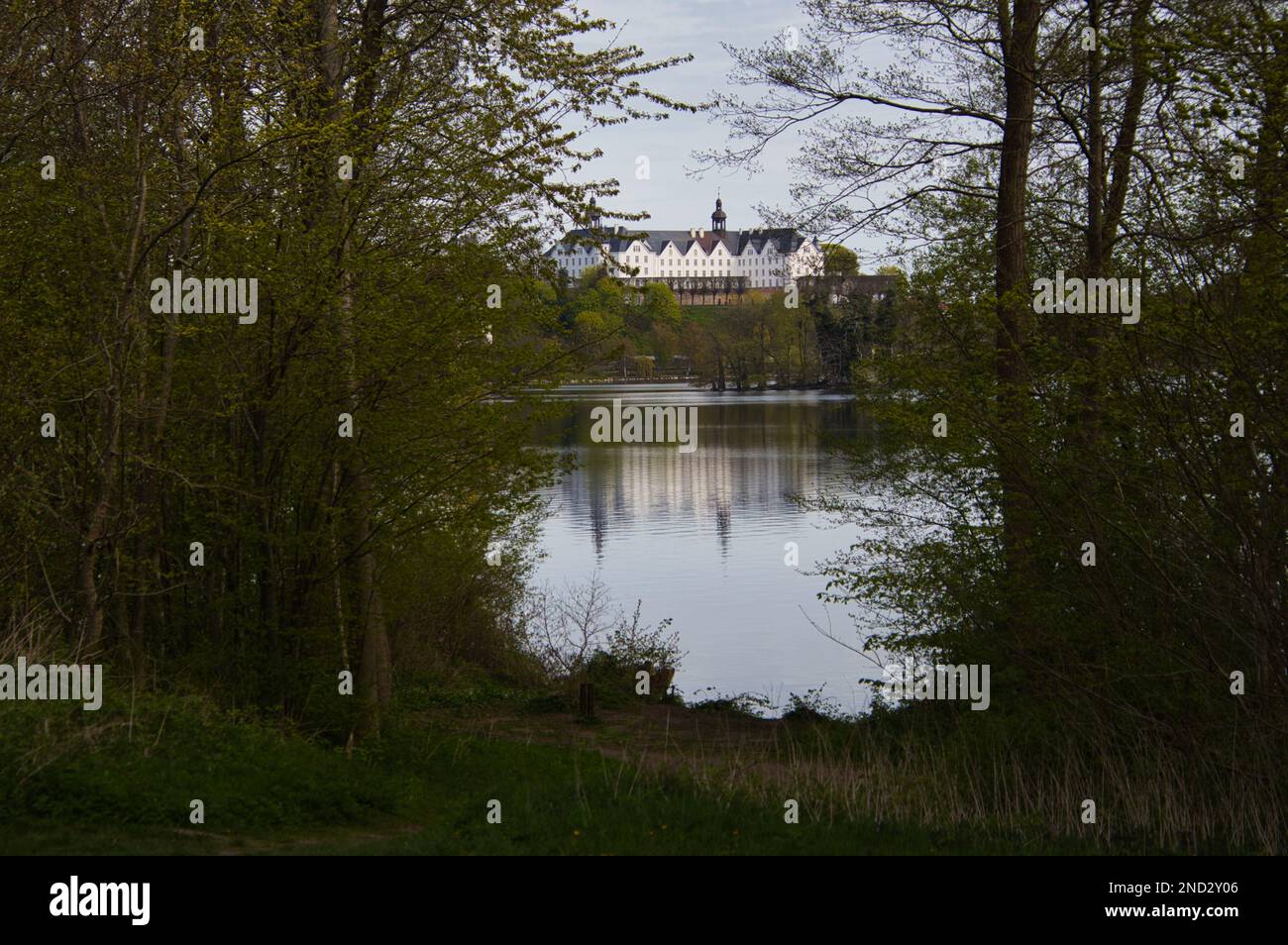 The Plon castle in Germany reflected in water between the trees Stock ...