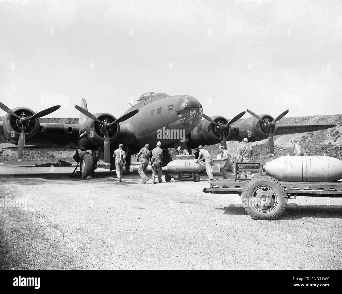 Members of a bomber service crew quickly load large bombs into a huge ...
