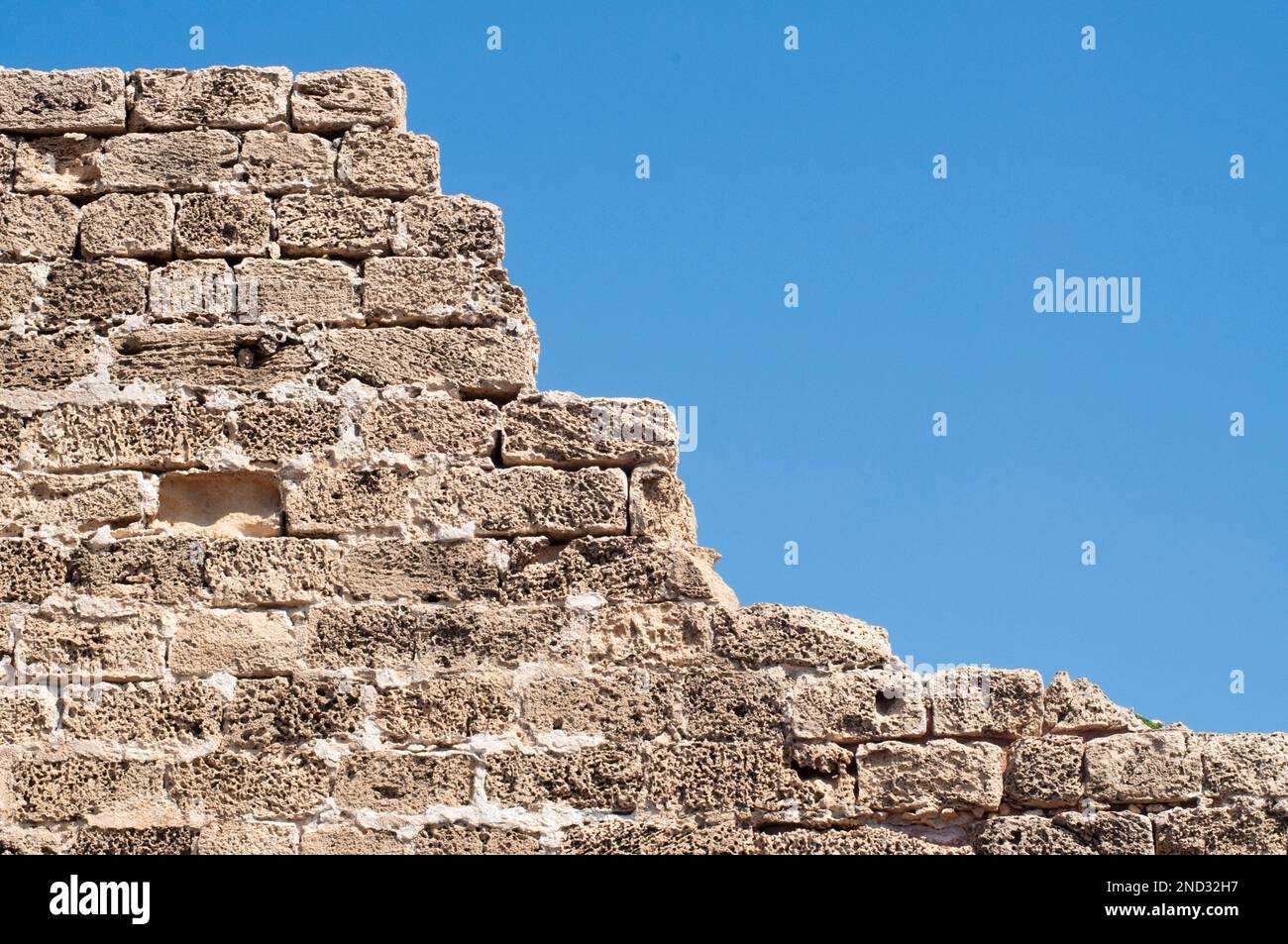 Ancient broken sandstone brick wall with the blue sky as the background ...