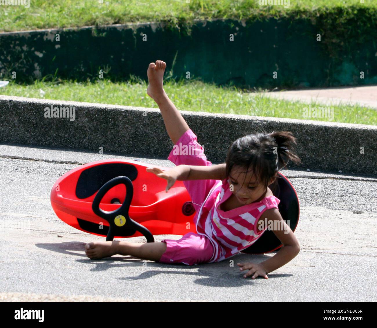 A girl tumbles to the ground while playing at Manila's Rizal Park ...