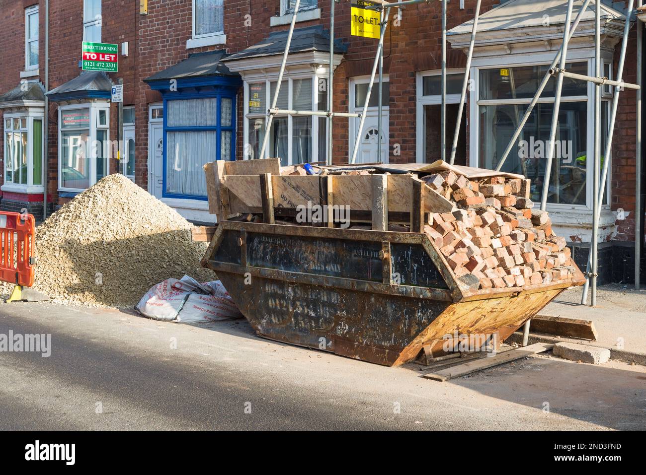 Building materials and a skip outside a terraced house being renovated ...