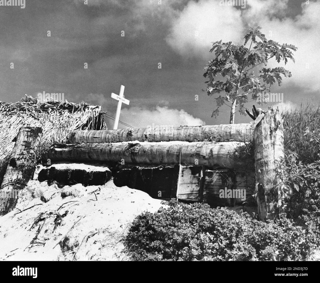 A lone white cross bearing the word “unknown” marks the grave of an ...