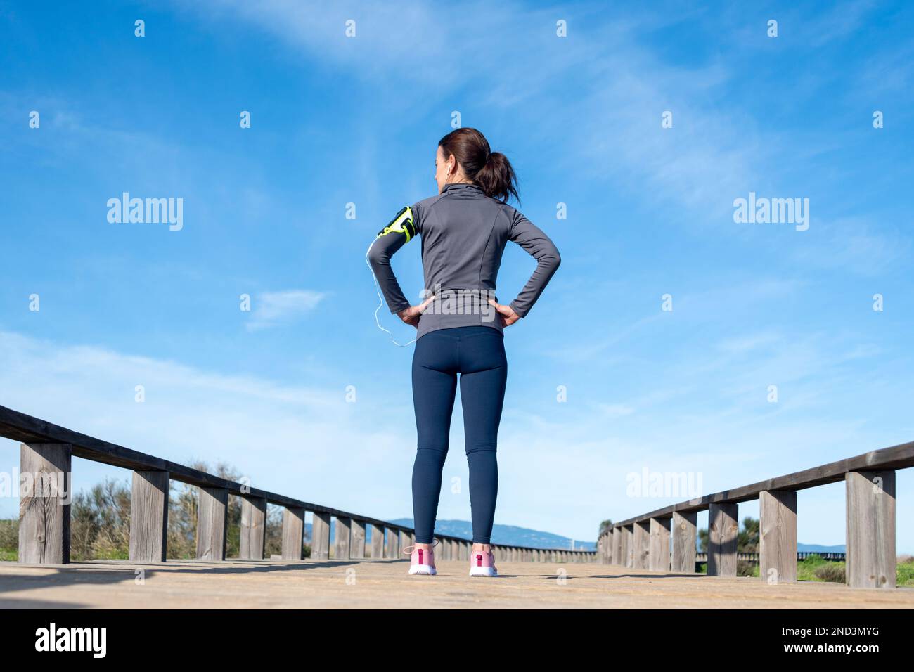 rear view of a female runner with her hands on her hips resting Stock ...