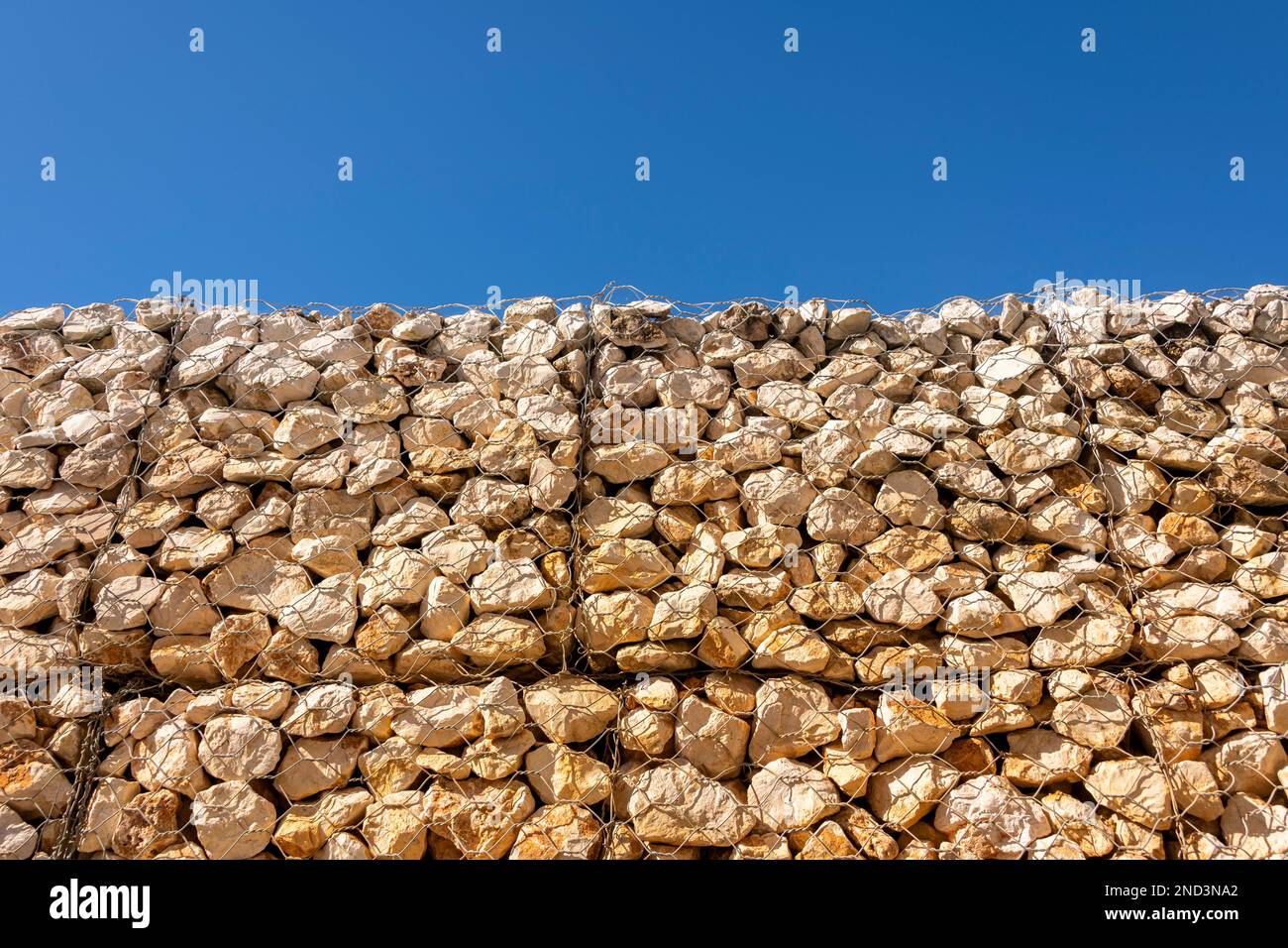 Gabion stone wall with blue sky background Stock Photo - Alamy