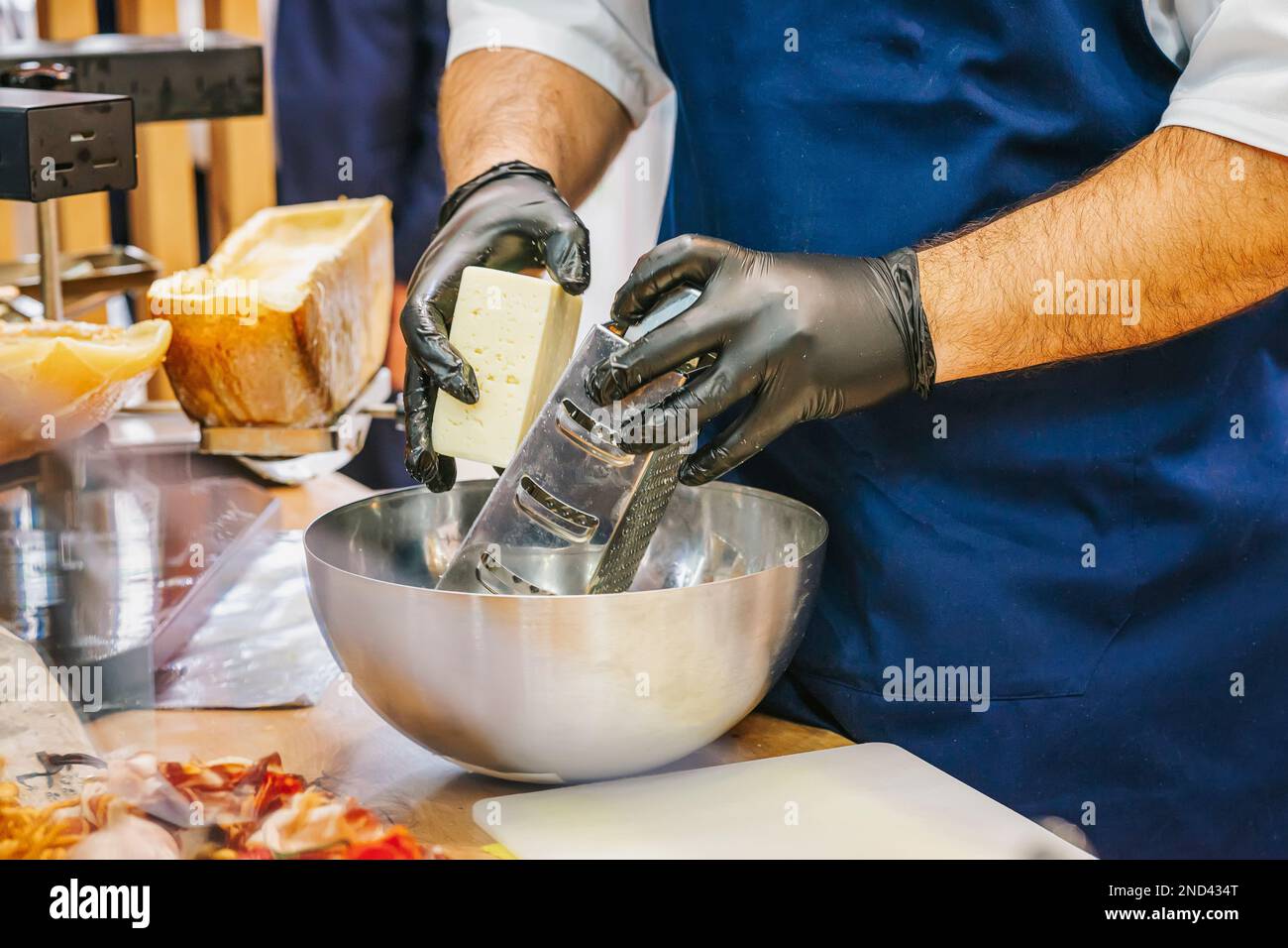 Chef grating cheese on steel grater in professional kitchen Stock Photo ...