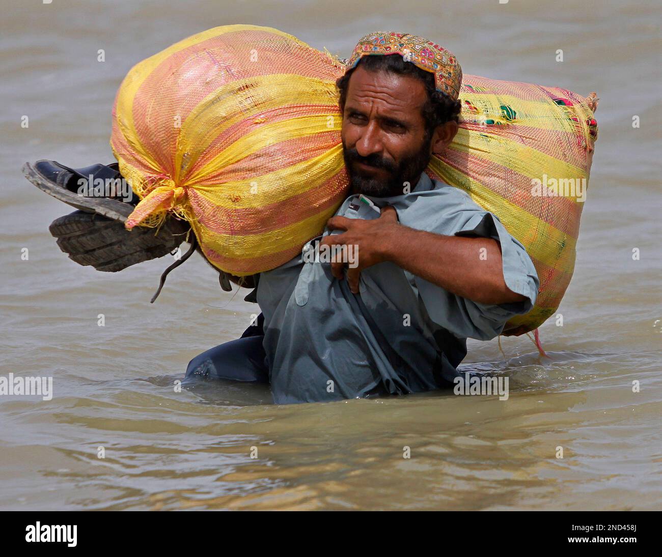 A Pakistani man carries his belongings along a flooded area at Sultan ...