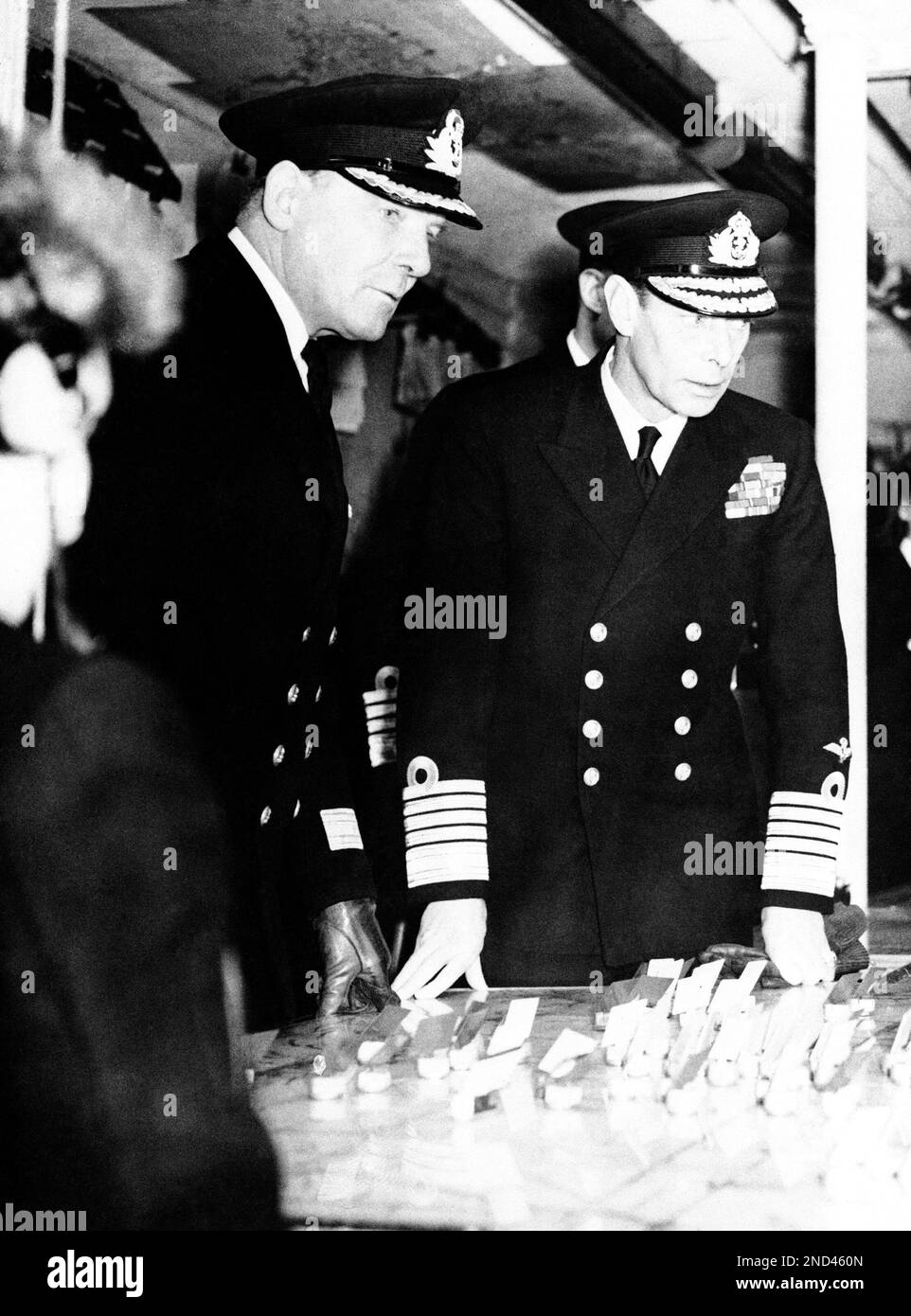 King George VI, right, inspects a naval chart with Commodore G. Bellars ...