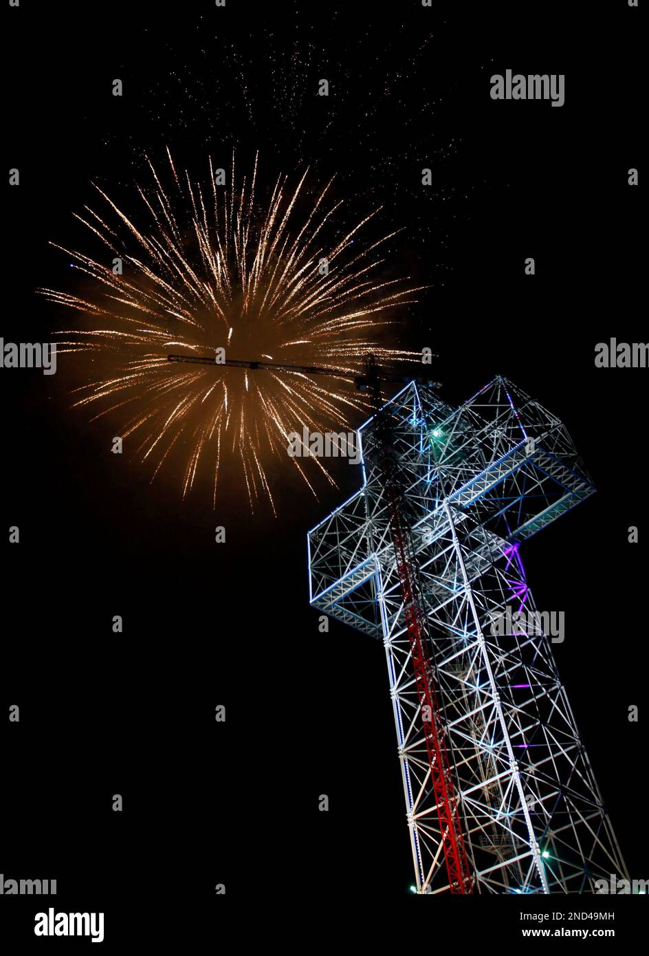 Fireworks light up the sky over a towering cross on the eve of the ...