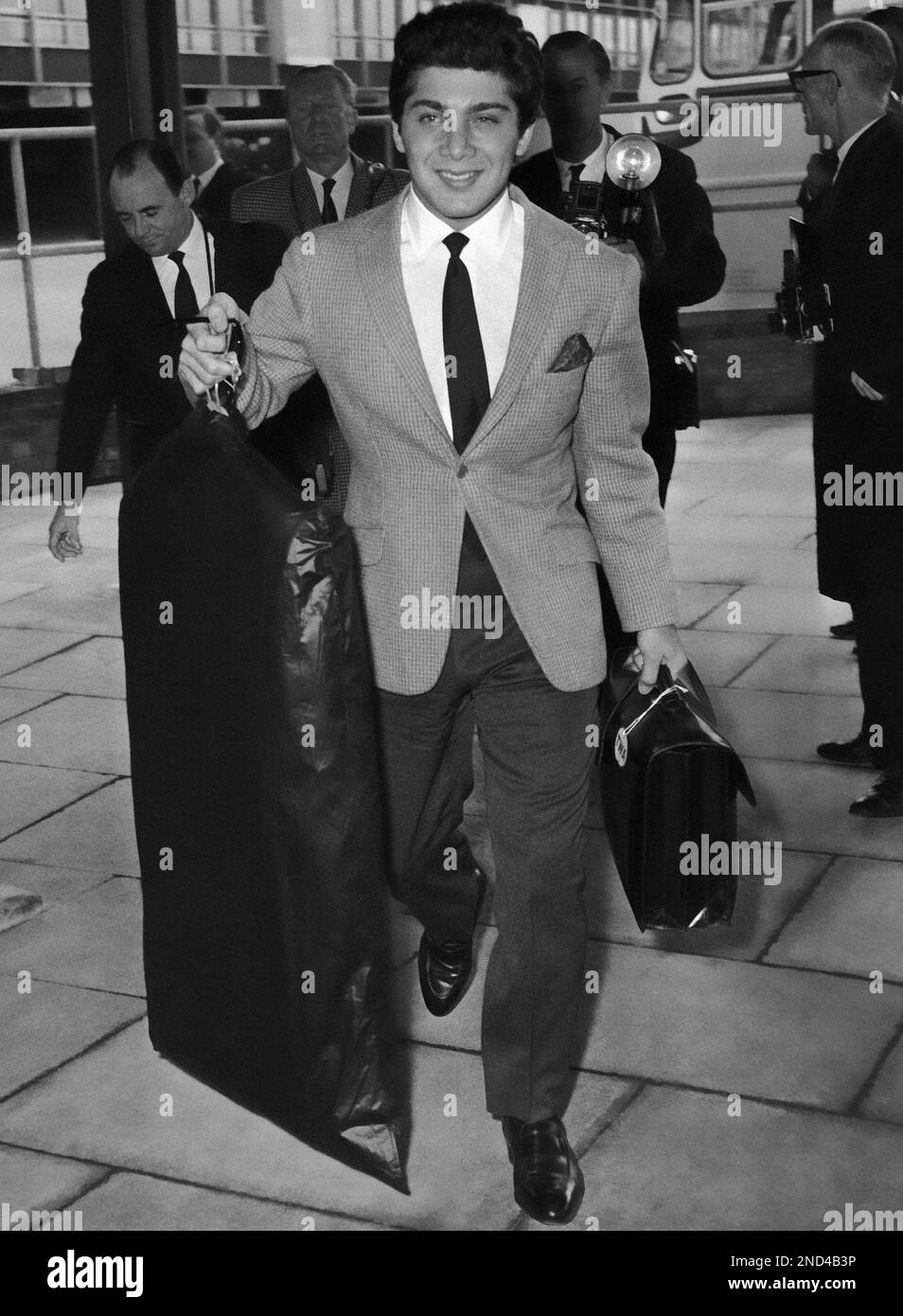 Pop singer Paul Anka carries a change of clothes as he bounds across ...