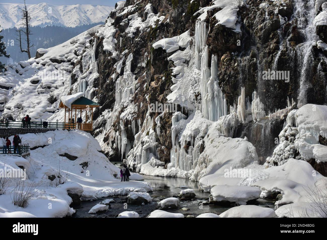 Visitors explore the frozen Drung waterfall on a sunny winter day in ...
