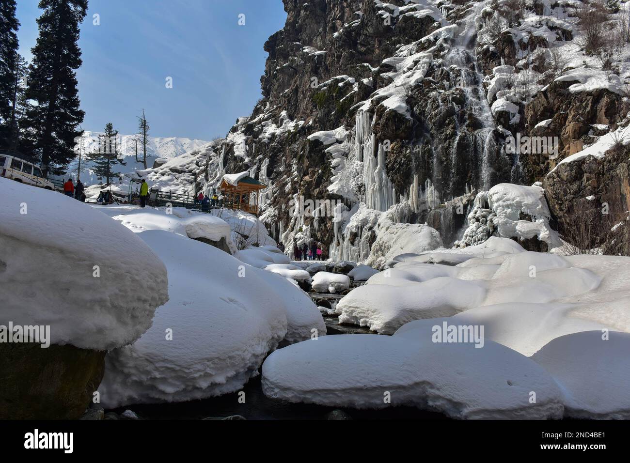 Visitors explore the frozen Drung waterfall on a sunny winter day in ...