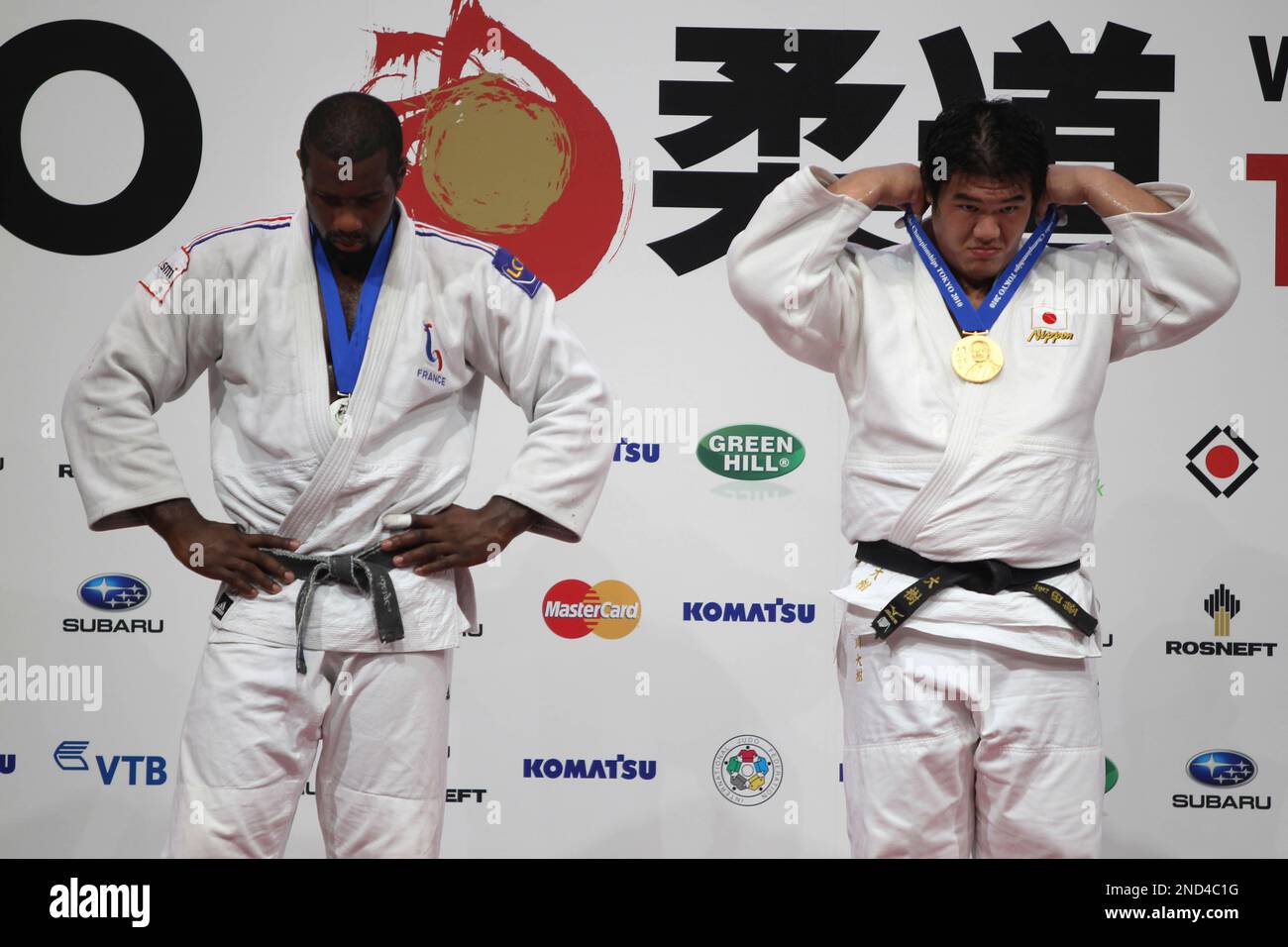 Teddy Riner, left, of France looks down on the medal podium after ...