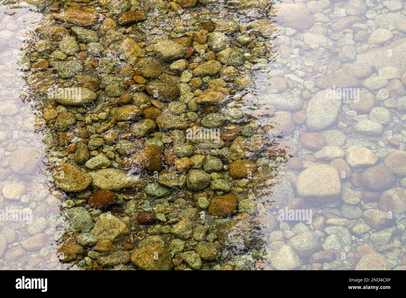 Rocks and crystal clear waters of the Merced River reflect the nearby ...