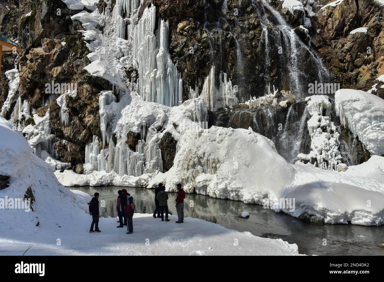 Indian tourists explore the frozen Drung waterfall on a sunny winter ...
