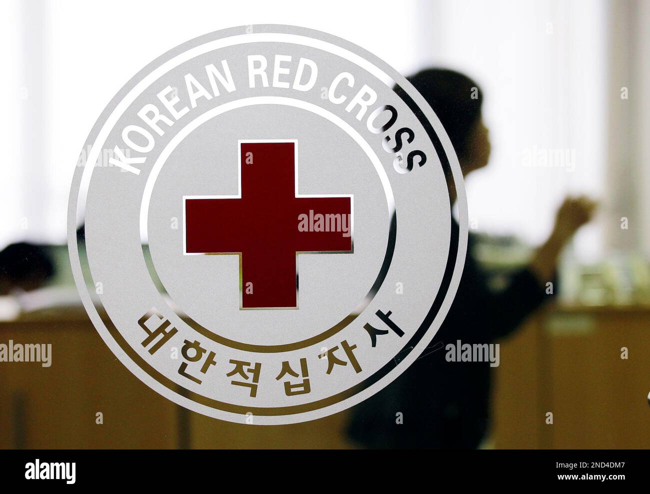 A Red Cross employee walks by the logo of the Korean Red Cross at it's ...