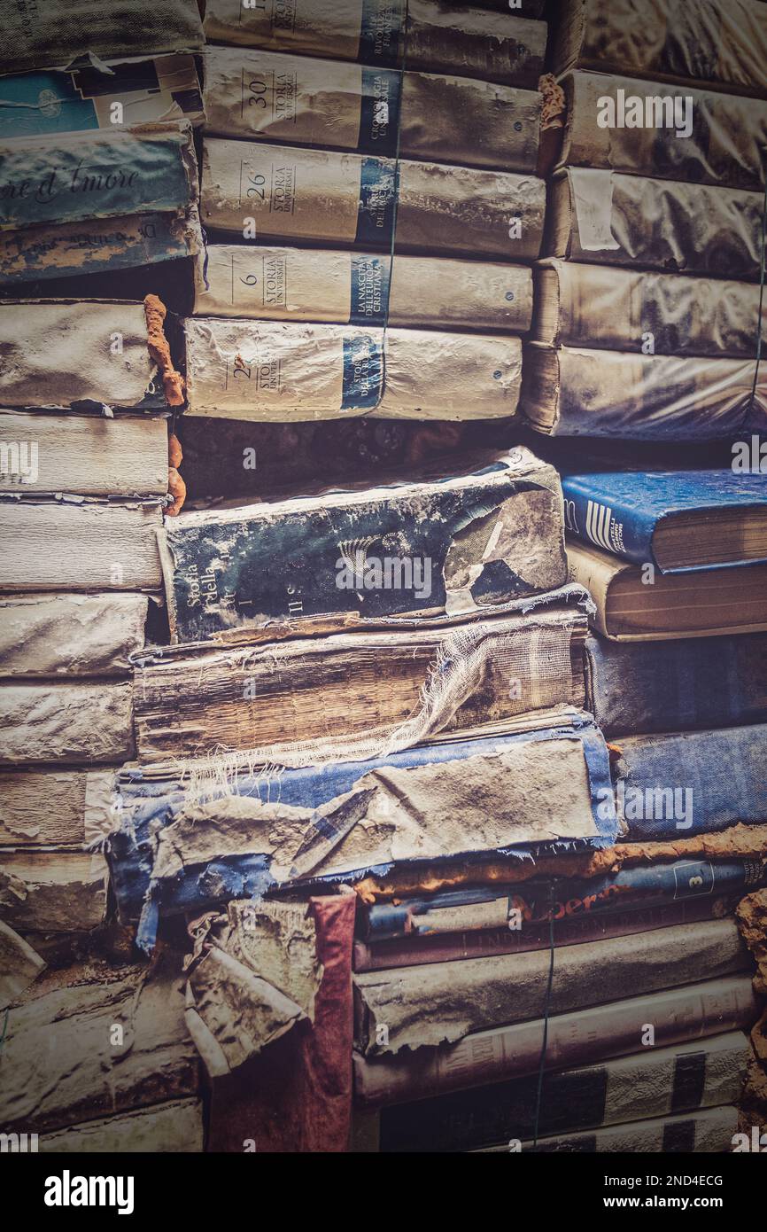 Piles of damaged hardback books on bookshelves in a back street ...