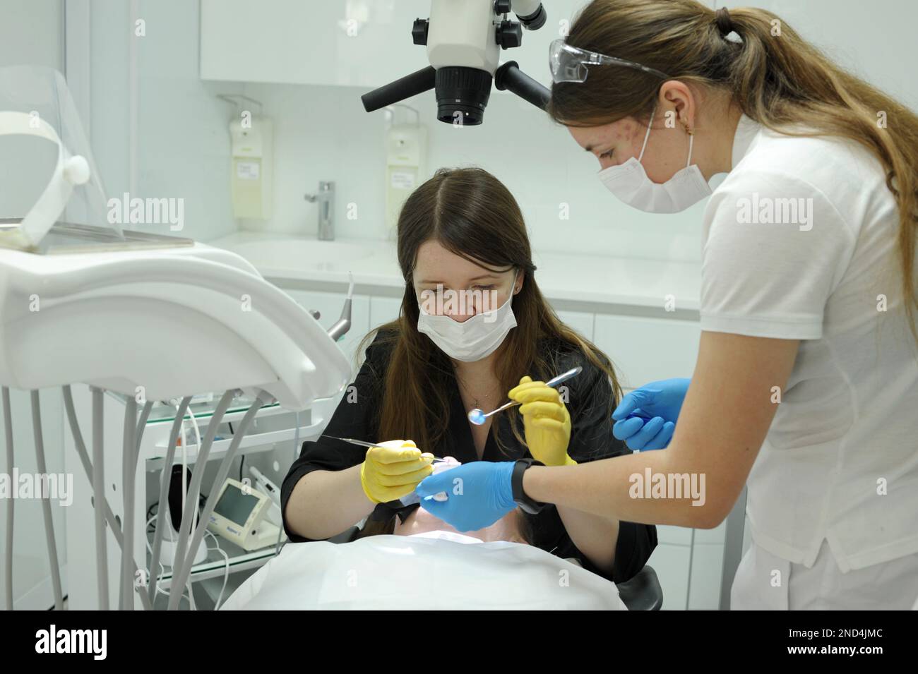 Female patient opening her mouth under the dental microscope and a ...