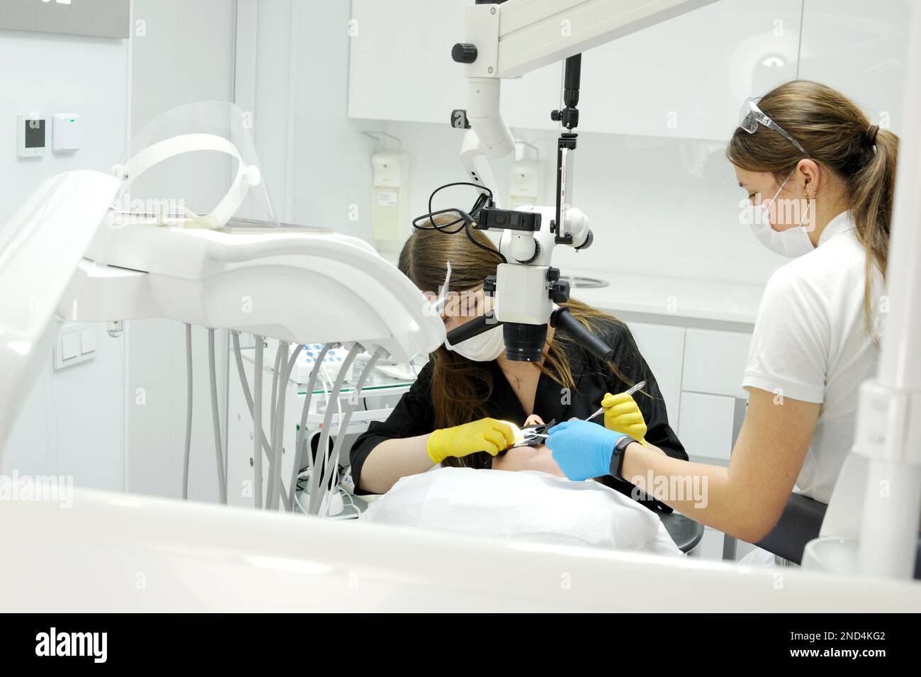 Female patient opening her mouth under the dental microscope and a ...