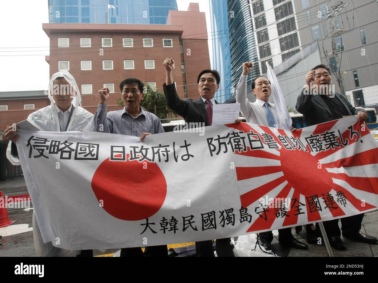 South Korean protesters with a Japanese national and wartime flag shout ...