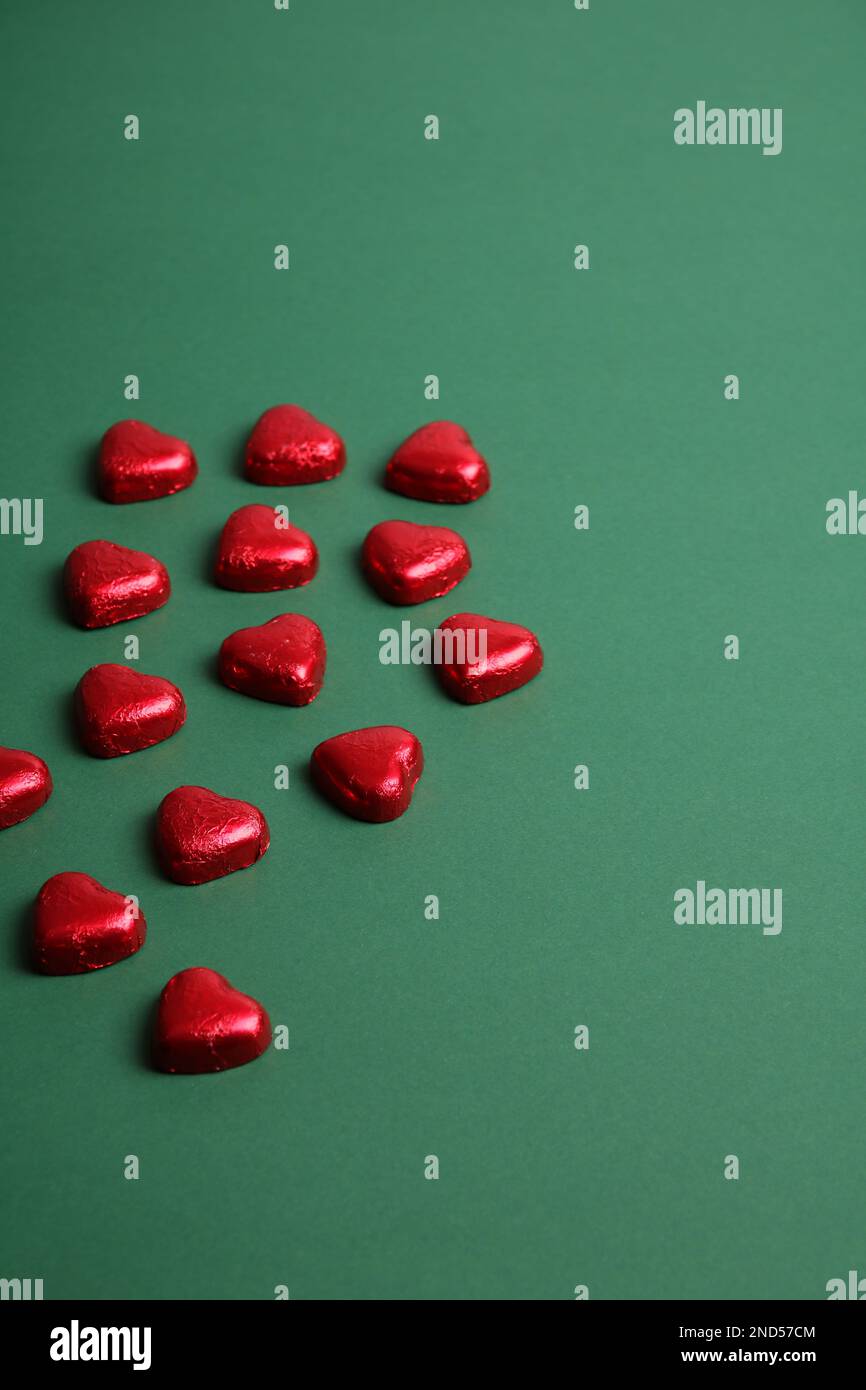 A photo of a lot of red candy in the shape of hearts on a homogeneous ...