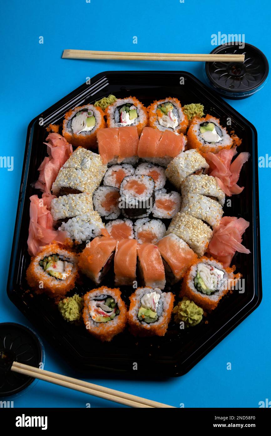 photo of a lot of sushi lying around in a package with wooden ...